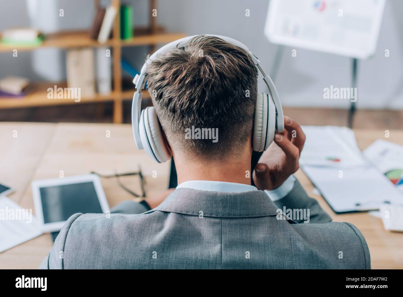Back view of businessman listening music in headphones near working ...