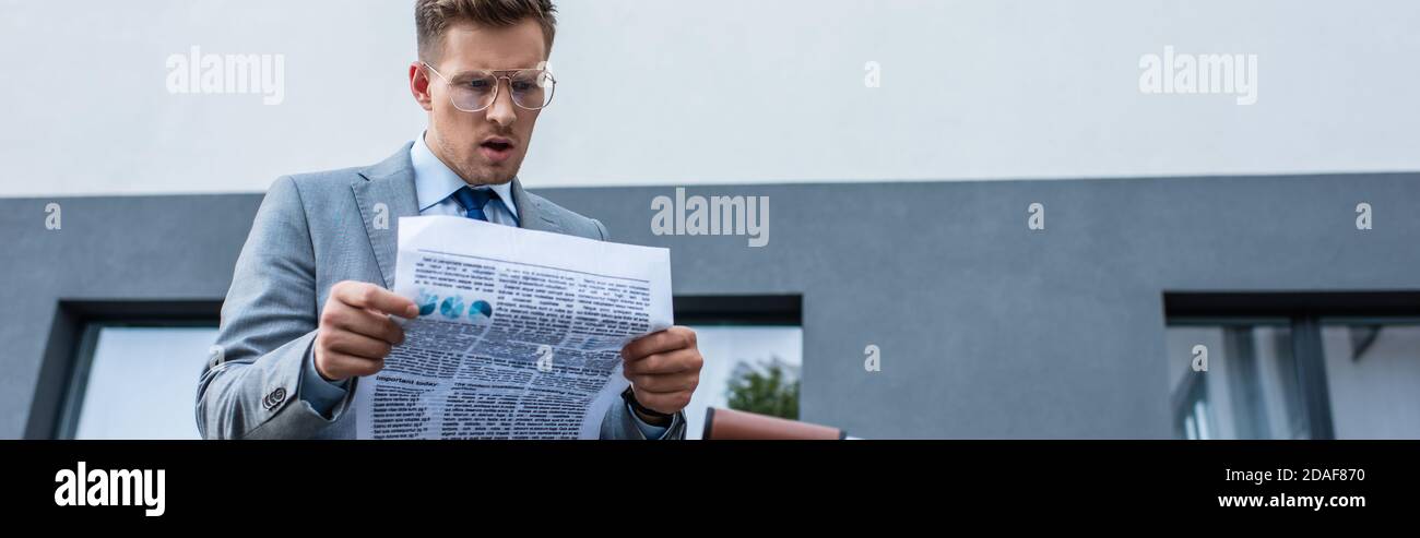 Concentrated businessman reading newspaper near building, banner Stock ...