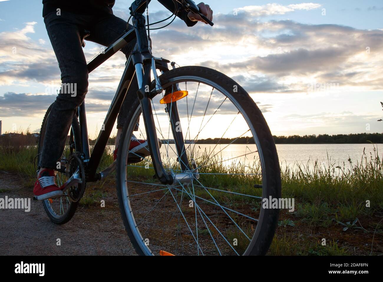 Wheel of a moving bicycle on the background of the lake and the setting ...