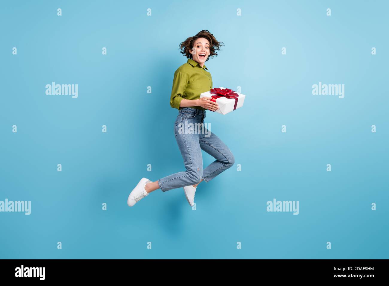 Photo portrait of excited girl jumping up holding red white present in ...