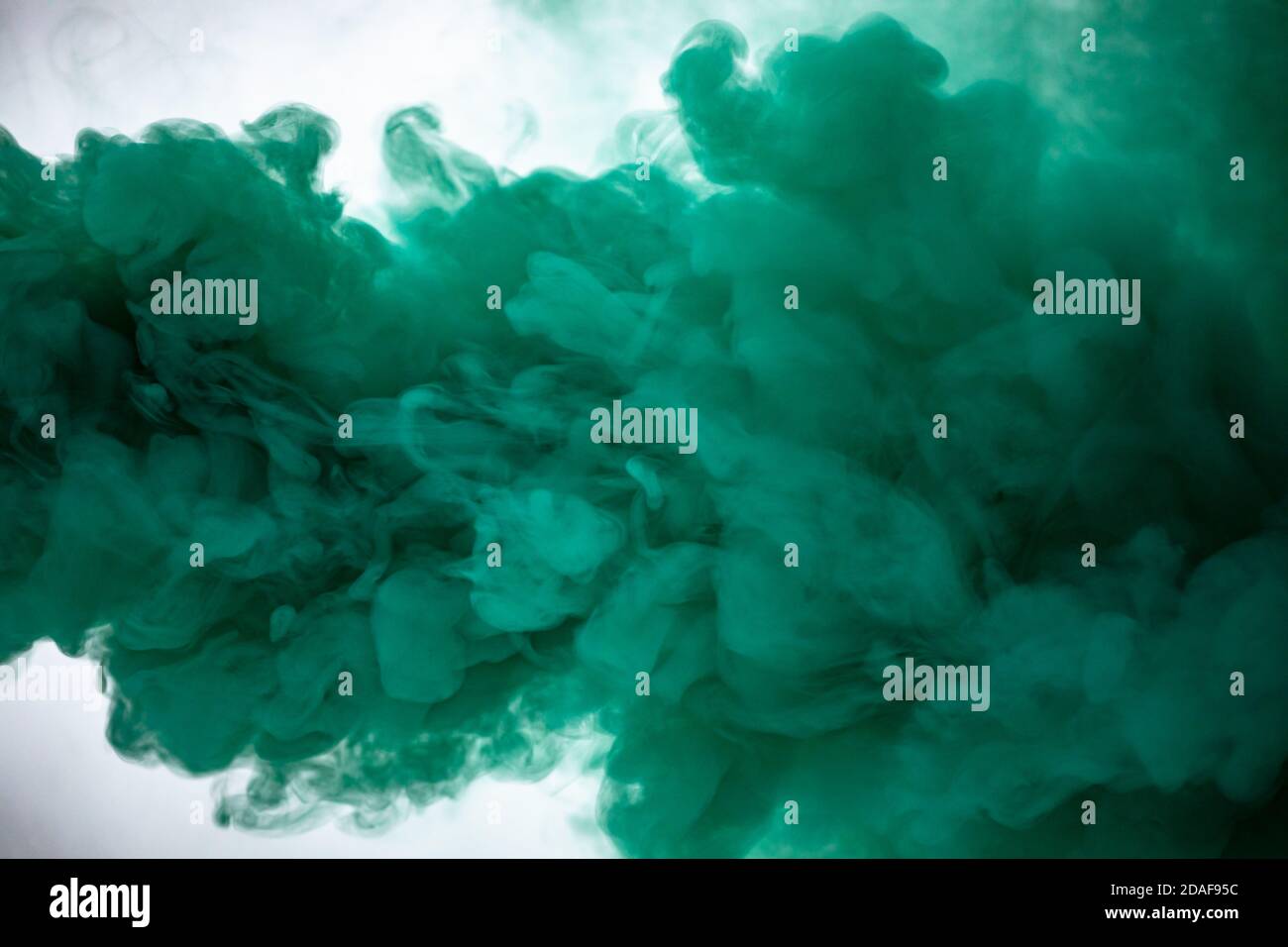 Green smoke bomb exploding against white background Stock Photo - Alamy