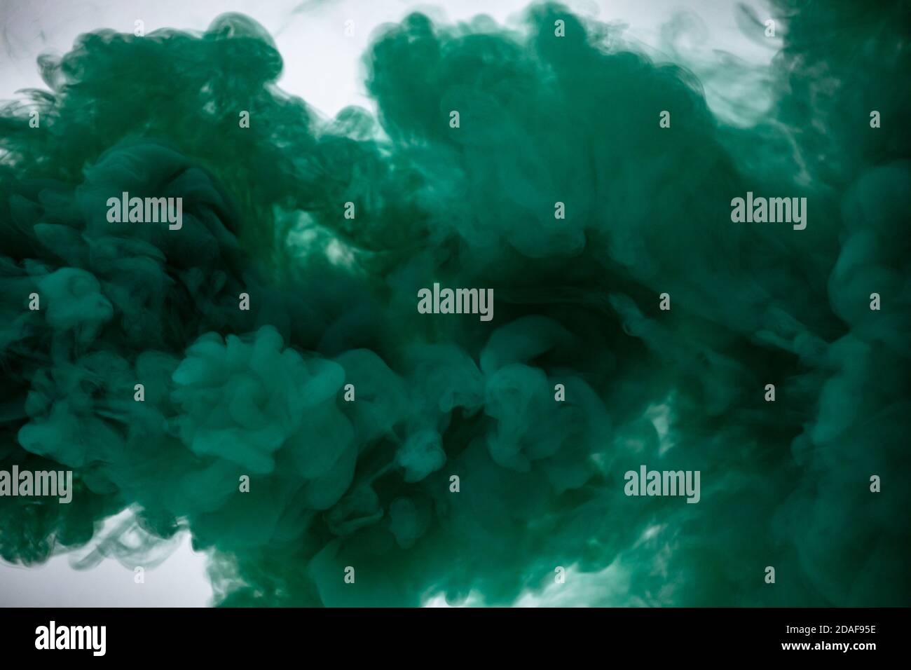 Green smoke bomb exploding against white background Stock Photo - Alamy