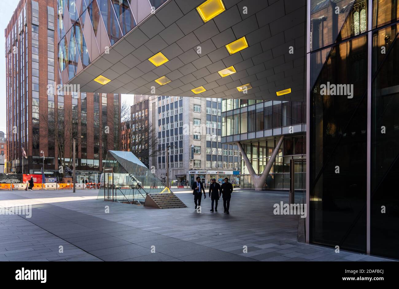 three small figures stand silhuetted amongst the huge buildings of ...