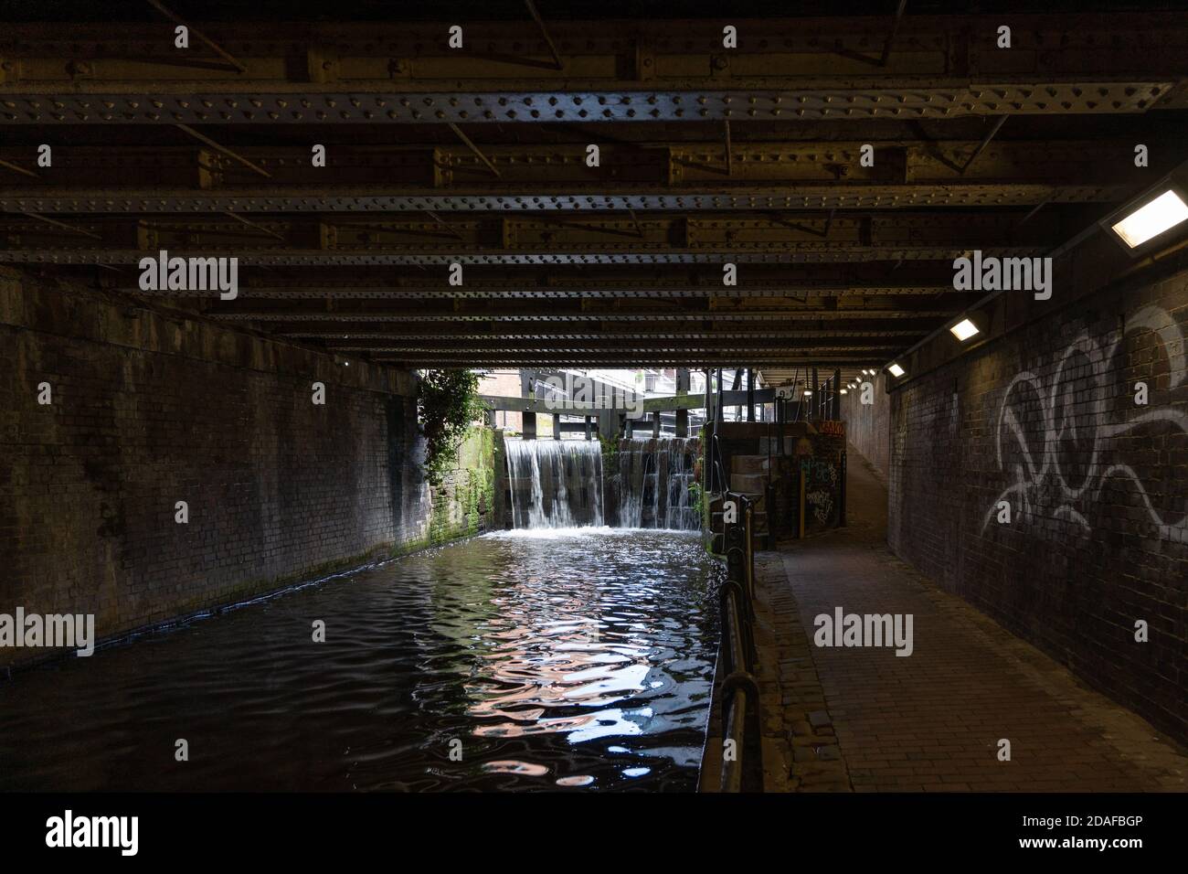 A low key image of water overflowing a lock gate, taken from under a ...