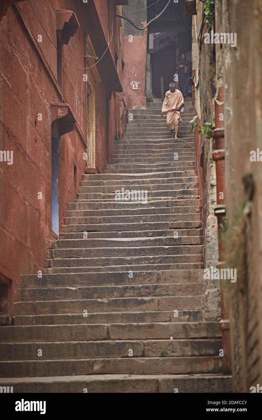 Varanasi, India, December 2015. A man descends long stairs in a ghat on ...