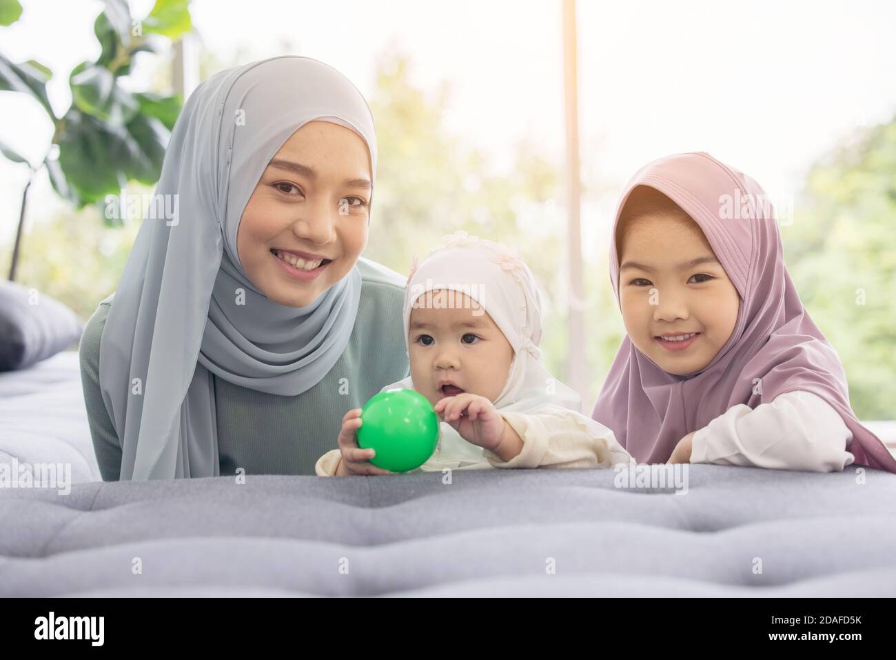 Muslim mom in hijab is her little daughter sitting in the living room ...