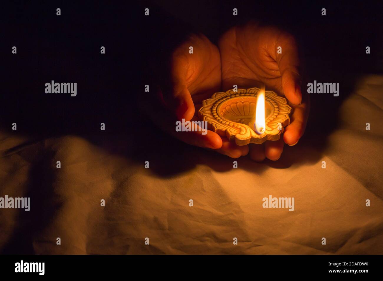 hands holding diwali diya or indian traditional oil lamp made of clay ...