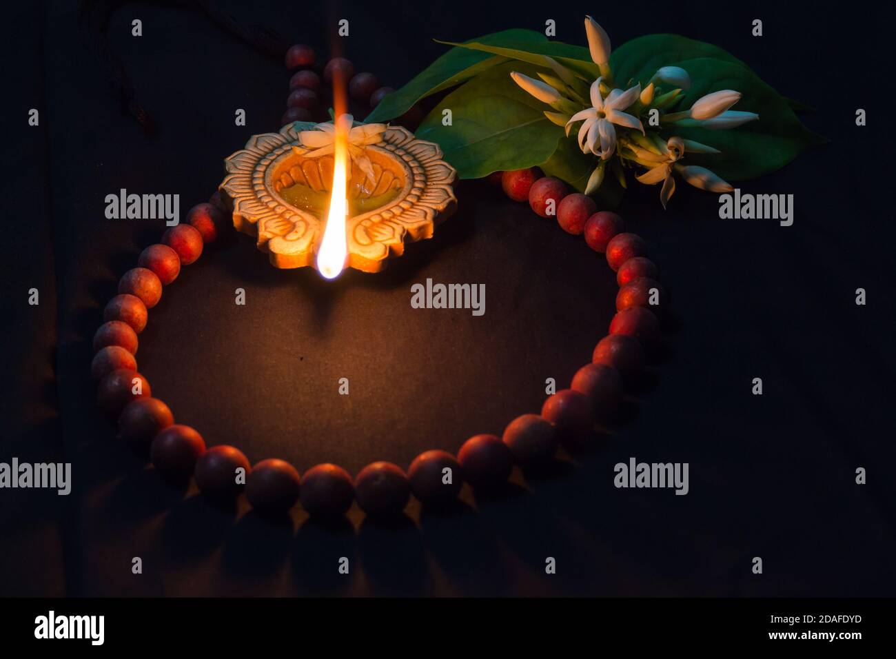 Indian traditional oil lamp made of clay with glowing flame, jasmine ...