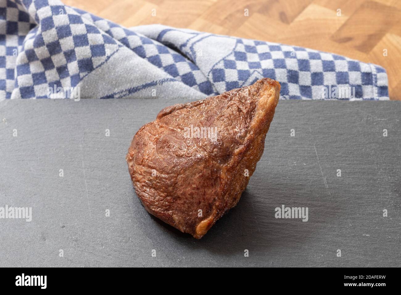 Piece of meat, Brazilian picanha in a gray plate and wooden kitchen ...