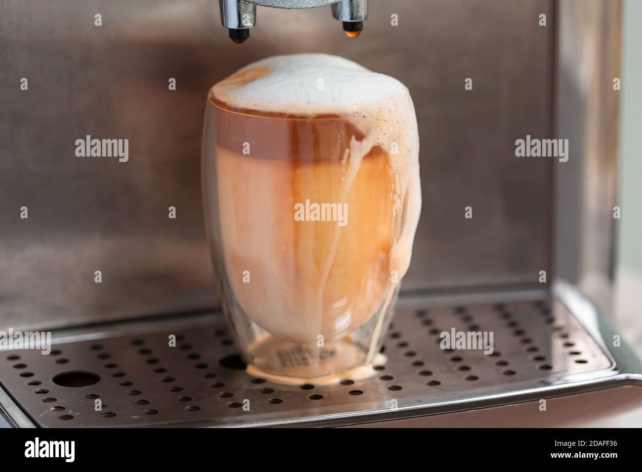 Coffee streaming from coffee machine and pouring out of glass full of ...