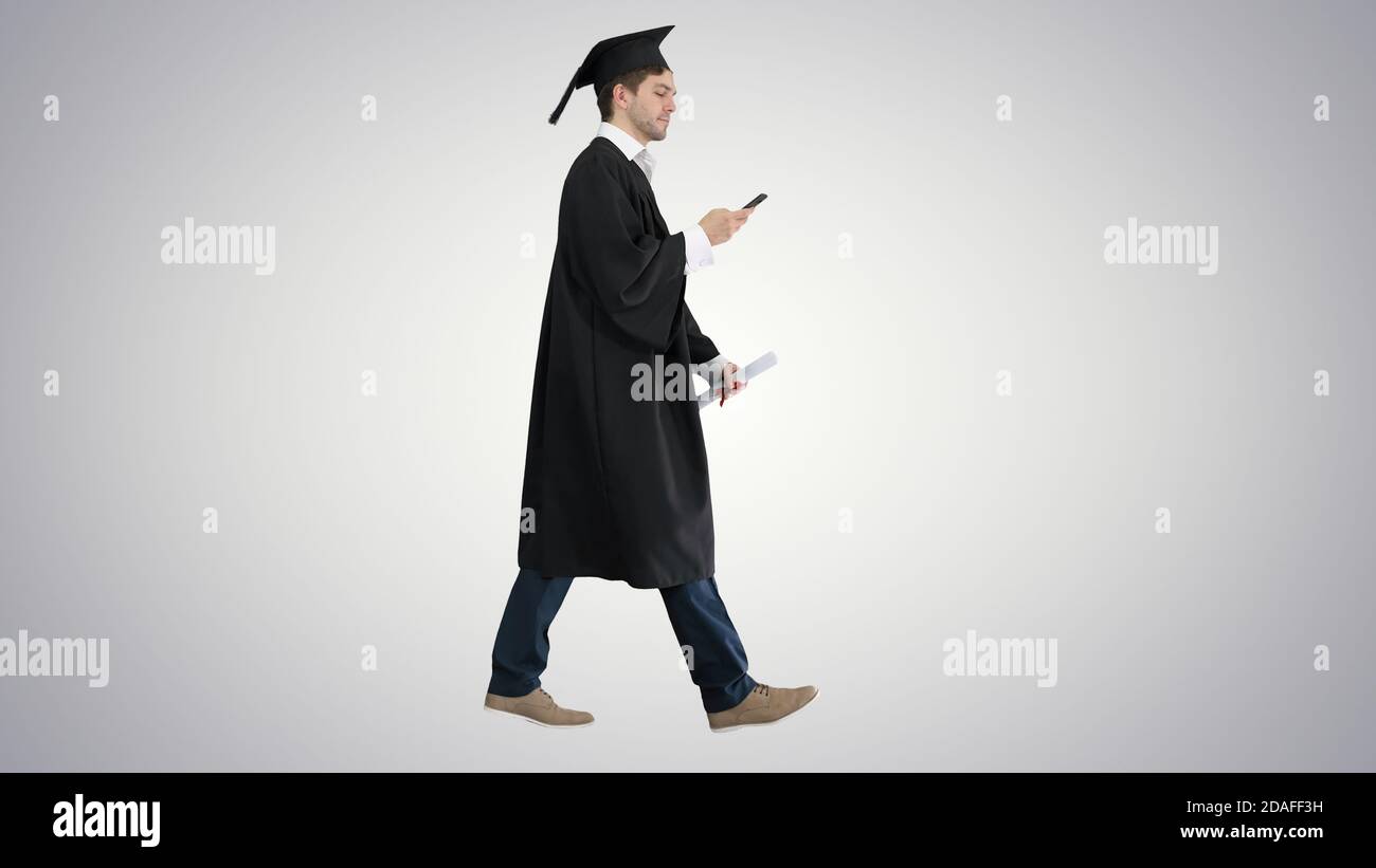 Male graduate student walking with his diploma and texting messa Stock ...