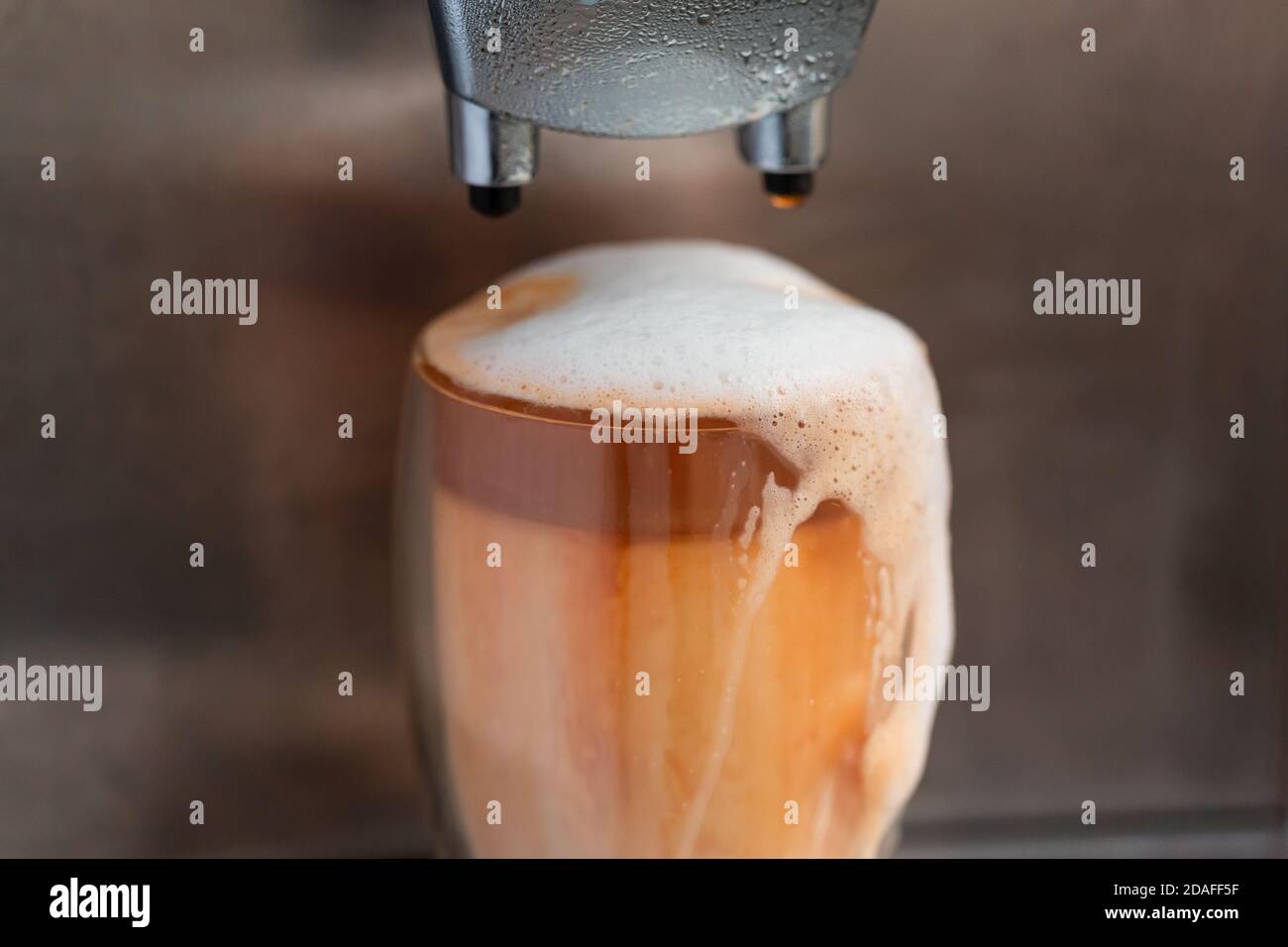 Coffee streaming from coffee machine and pouring out of glass full of ...