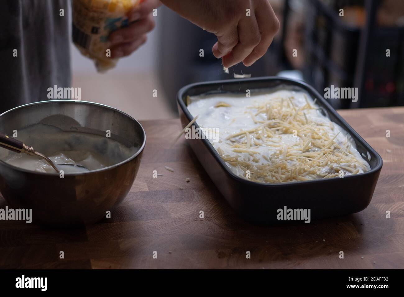 Preparing lasagne, hand pouring grated cheese Stock Photo - Alamy