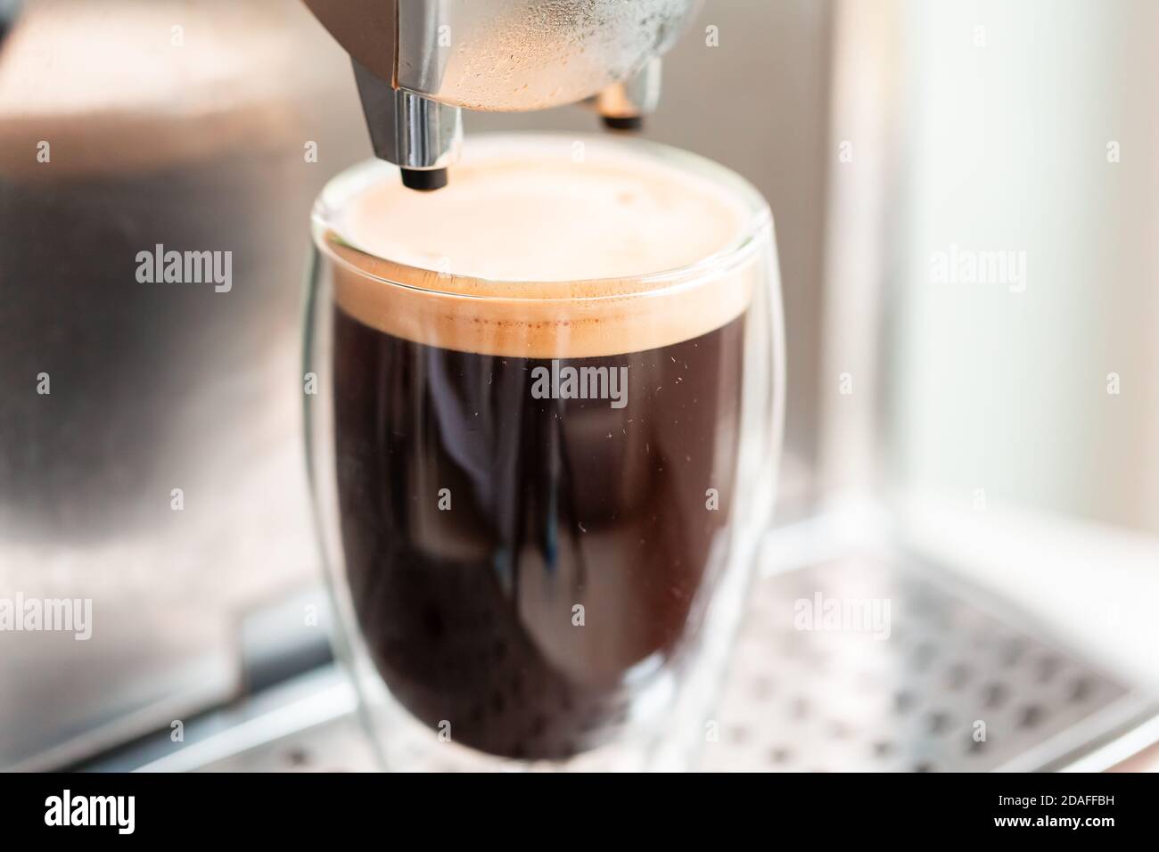 Coffee espresso streaming from coffee machine and pouring into glass ...