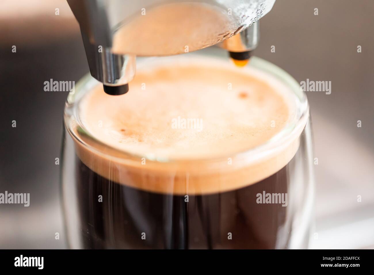 Coffee espresso streaming from coffee machine and pouring into glass ...