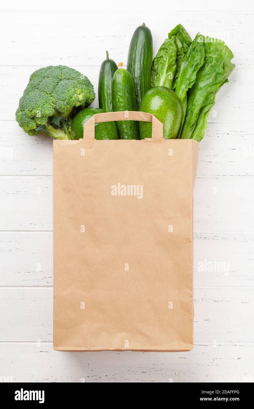 Different green healthy food in recycling paper bag on wooden table ...