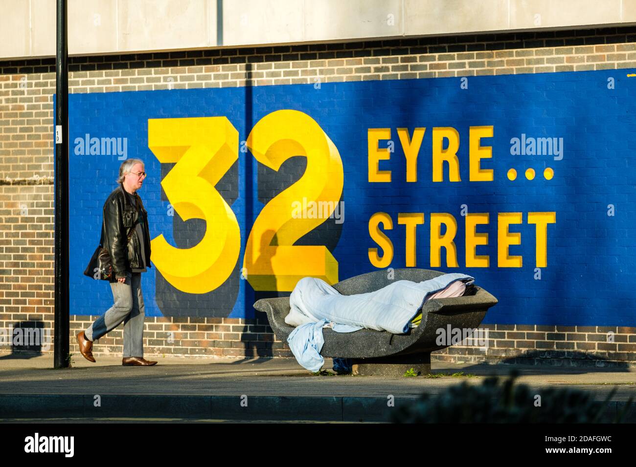 Pedestrian walking past a man sleeping rough on day 4 of the lockdown ...