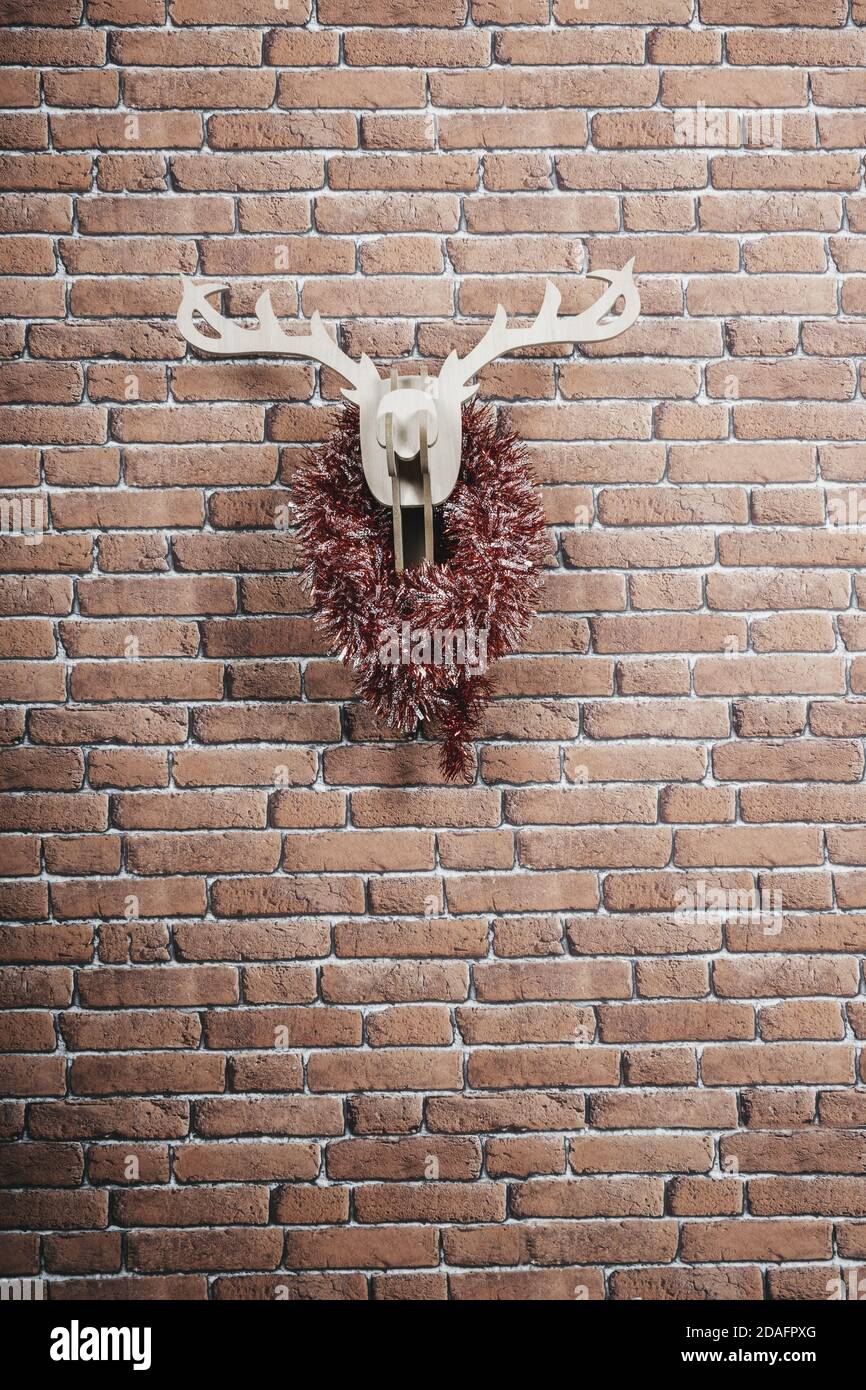 Wooden deer hanging on the brick wall decorated with Christmas garlands ...