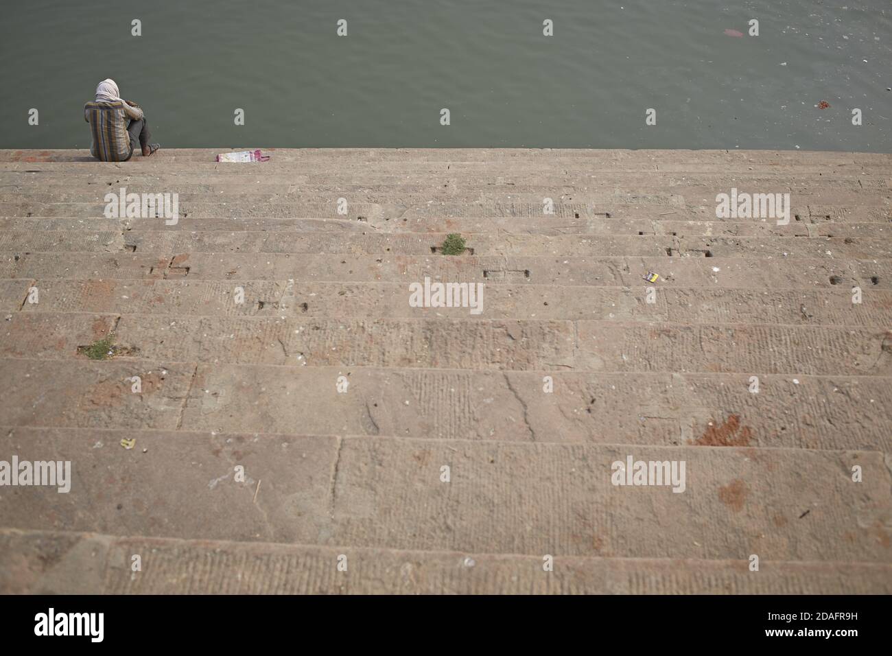 Varanasi, India, December 2015. A man sitting on the step of a ghat in ...