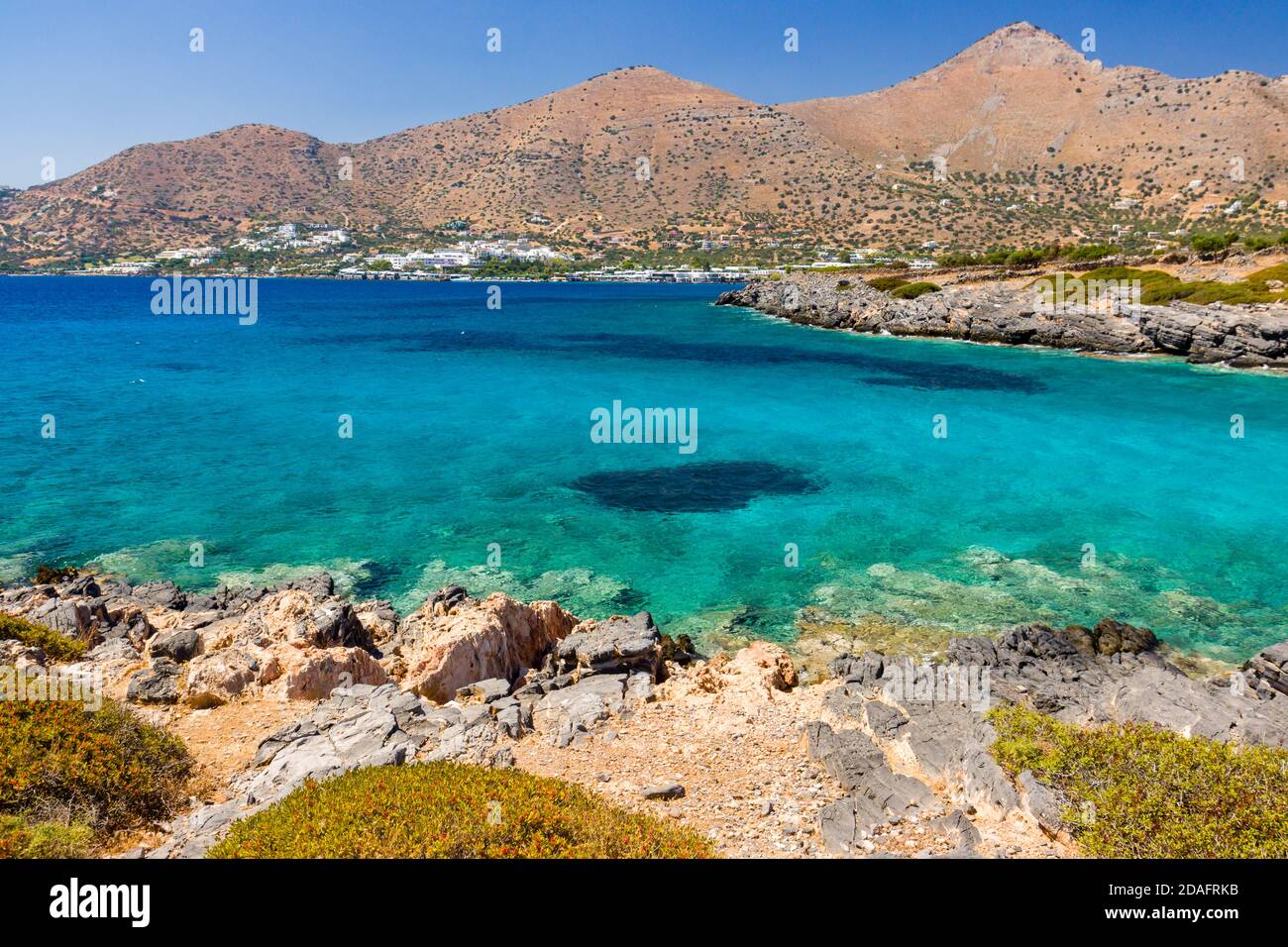 Crystal clear ocean next to a dry, rocky coastline on the Greek island ...