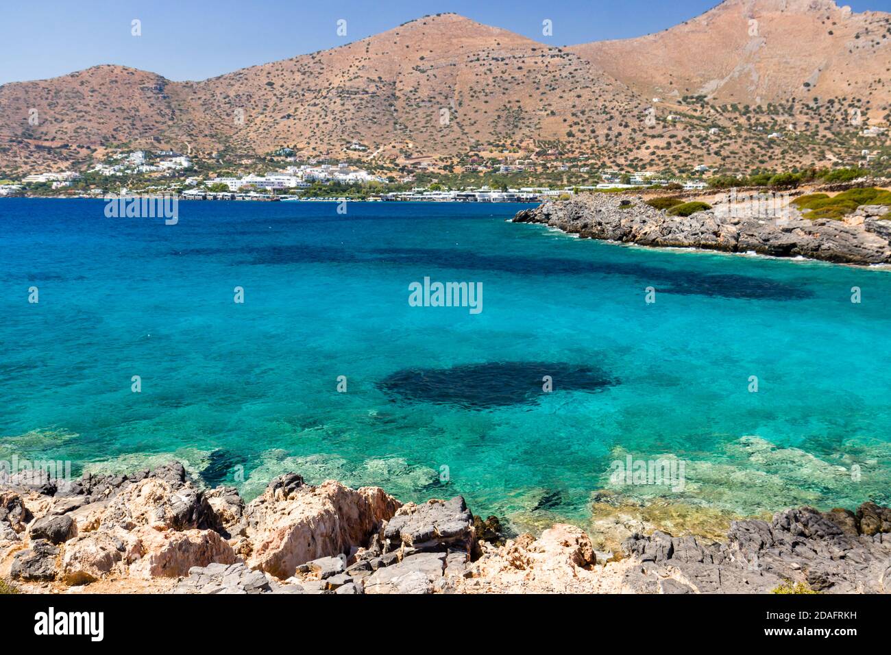 Crystal clear ocean next to a dry, rocky coastline on the Greek island ...