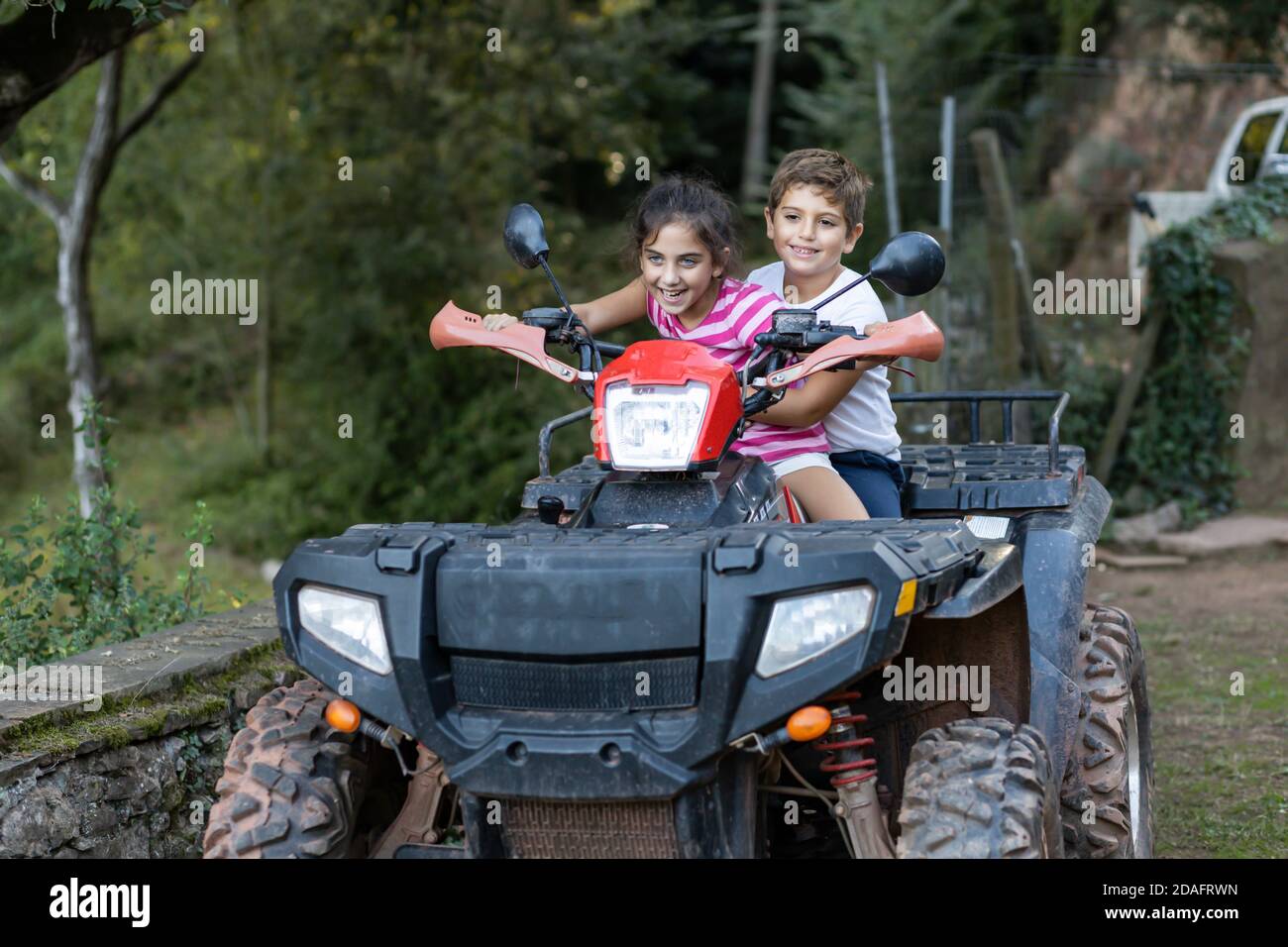 Two little kids riding a quad Stock Photo - Alamy