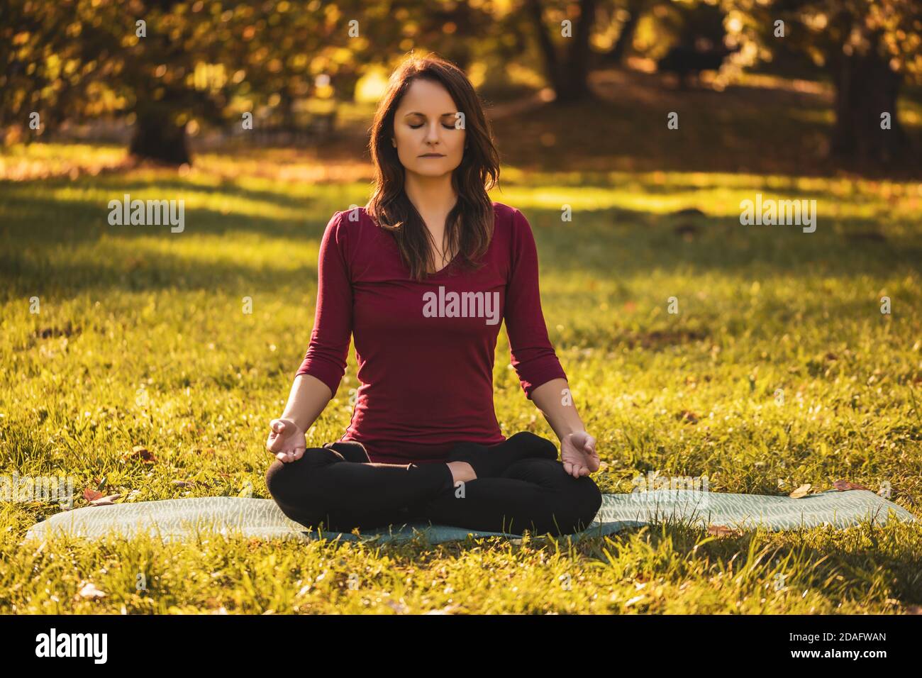 Beautiful woman sitting in lotus position and meditating in the nature ...