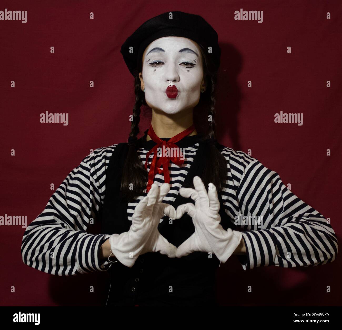 Beautiful girl mime smiles and makes a gesture of a beating heart with ...