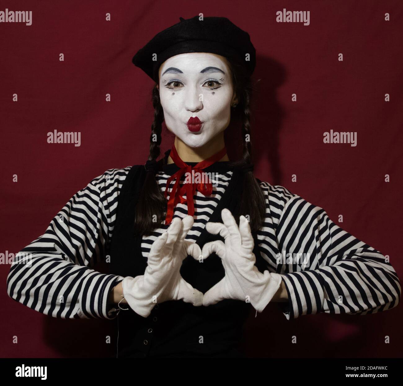 Beautiful girl mime smiles and makes a gesture of a beating heart with ...