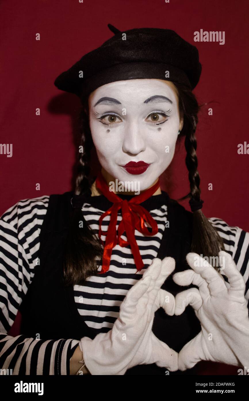 Beautiful girl mime smiles and makes a gesture of a beating heart with ...