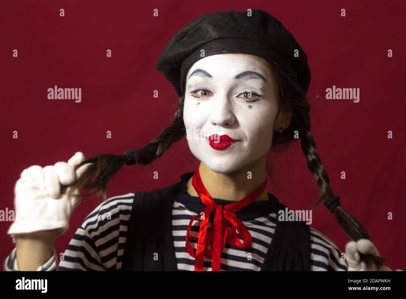 Beautiful mime girl smiles and holds her pigtails with her hands Stock ...