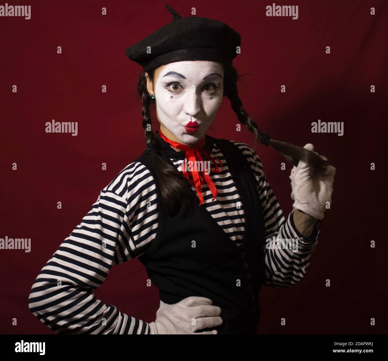 Beautiful mime girl smiles and holds her pigtails with her hands Stock ...