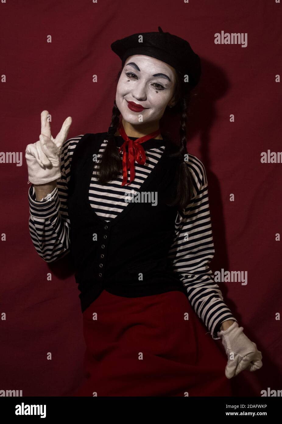 Beautiful mime girl grimaces and shows a victory sign with her hand ...