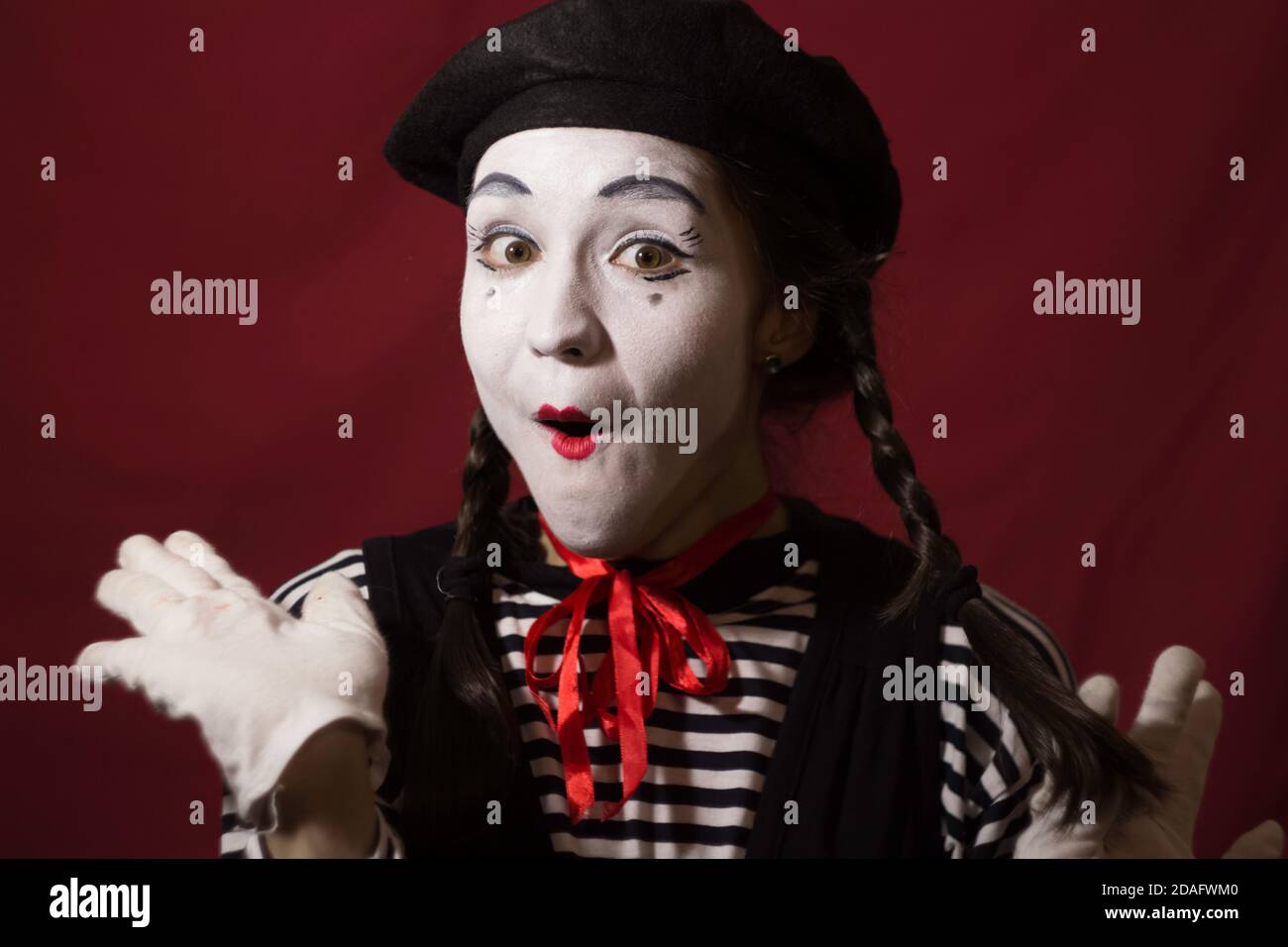 Beautiful mime girl grimaces and holds her pigtails with her hands ...