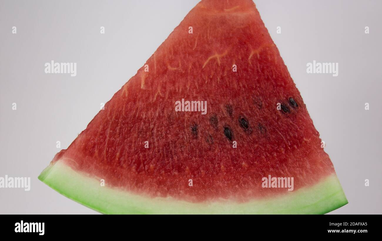 A slice of ripe watermelon rotates on a plate. Close up of watermelon ...
