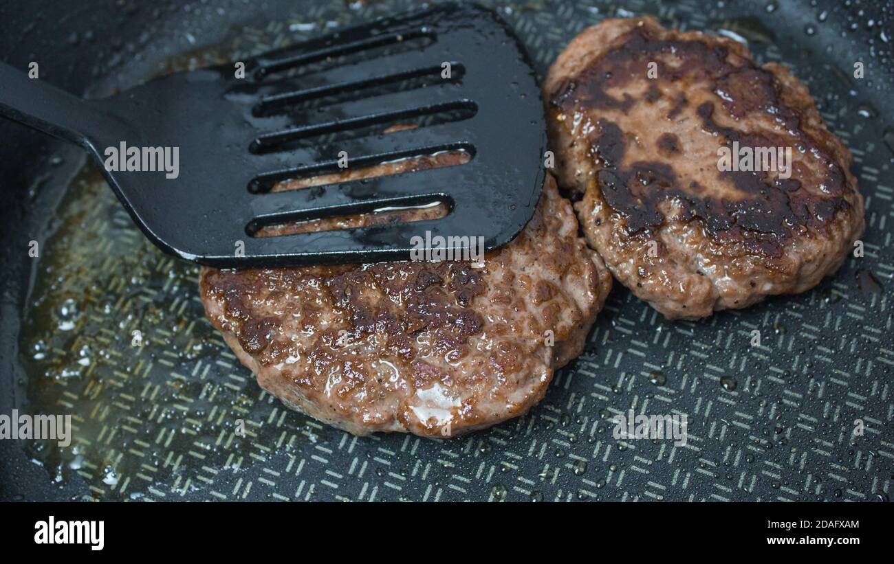 The chef puts beef patties into a frying pan. Juicy beef cutlet is ...
