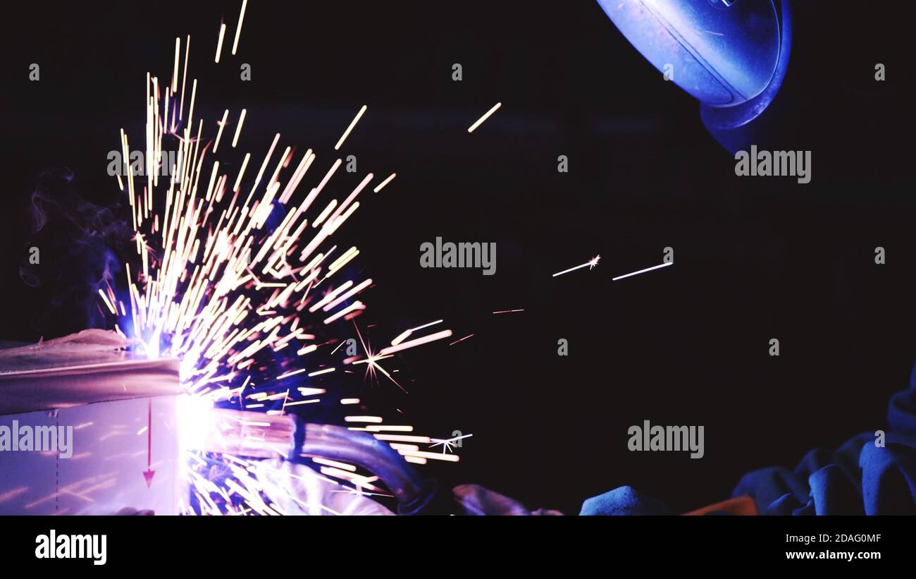 worker wears welder protective mask while welding metal with sparks in ...