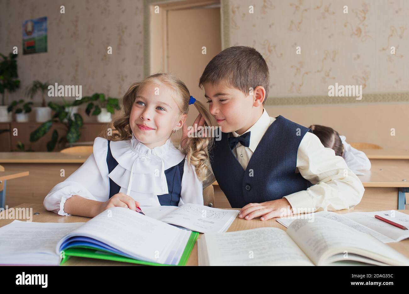 two students a boy and a girl sit at a Desk at school and communicate ...