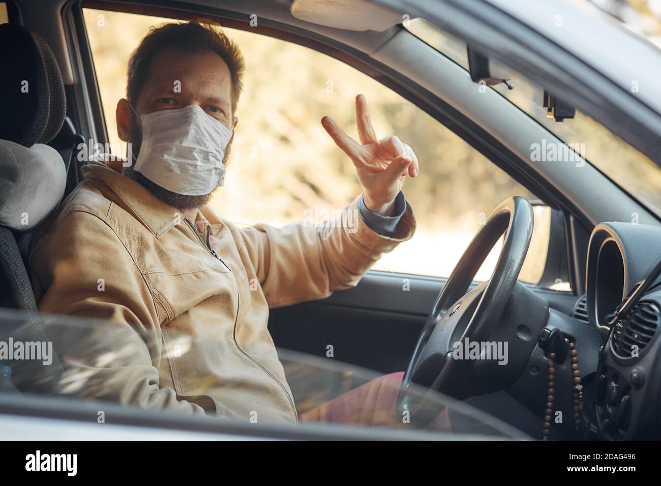 a man driving a car puts on a medical mask during an epidemic, a taxi ...
