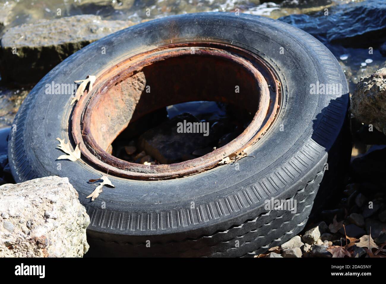 A tire between rocks next to water Stock Photo - Alamy