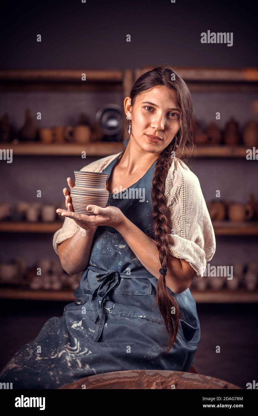 Stylish handicraftsman master shows how to work with clay and pottery ...