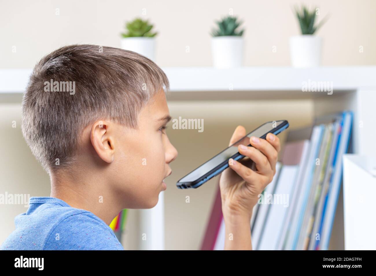 Teenage boy doing homework, using cell phone recording and send a voice ...