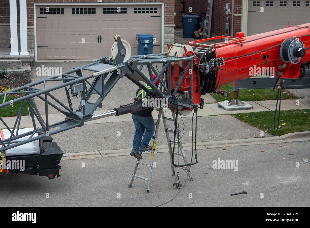 The crane operator prepares the crane for work, attaches an additional section by extending the ...