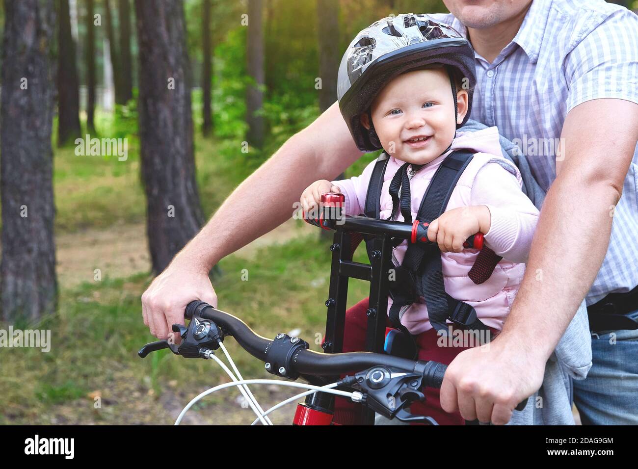 Close-up baby in a bicycle seat on a bicycle with dad. Family and ...
