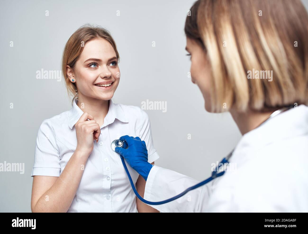 Doctor with a stethoscope and a happy patient on a light background ...