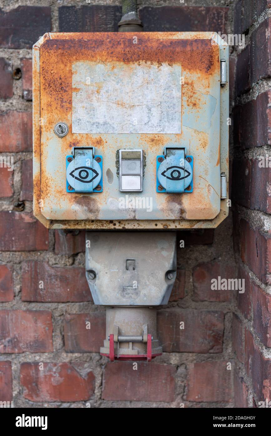 Rusty outdoor electrical outlet with eyes on red brick wall Stock Photo ...