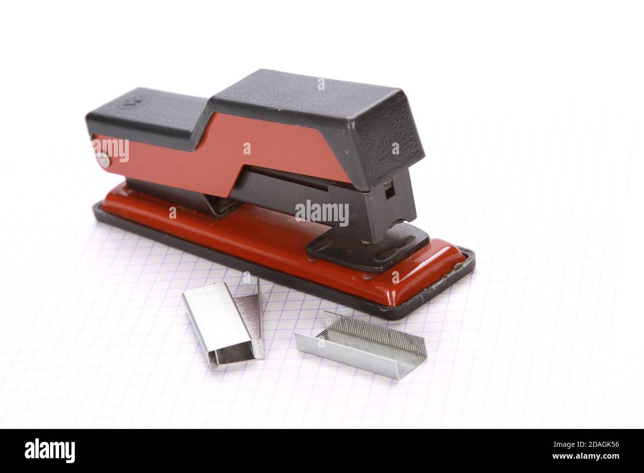Red and black stapler with extra staples on squared paper Stock Photo ...