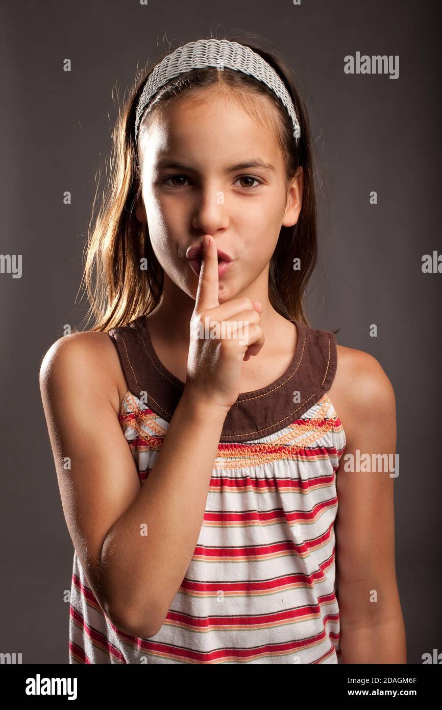 little girl showing silence gesture on a gray background Stock Photo ...