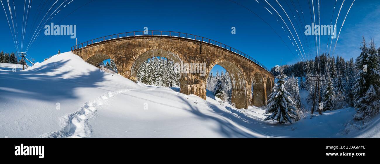 Stone viaduct (arch bridge) on railway through mountain snowy fir ...