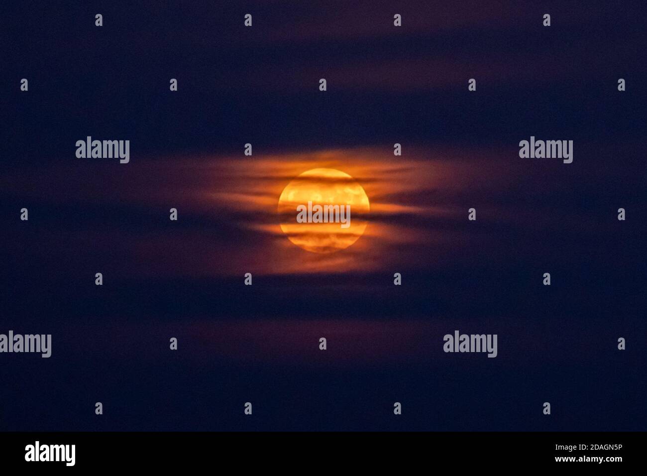 huge orange full moon peeking through misty clouds illuminating the ...